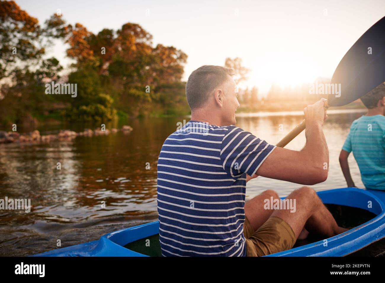 Paddling off into the sunset. a father and son rowing a boat together ...
