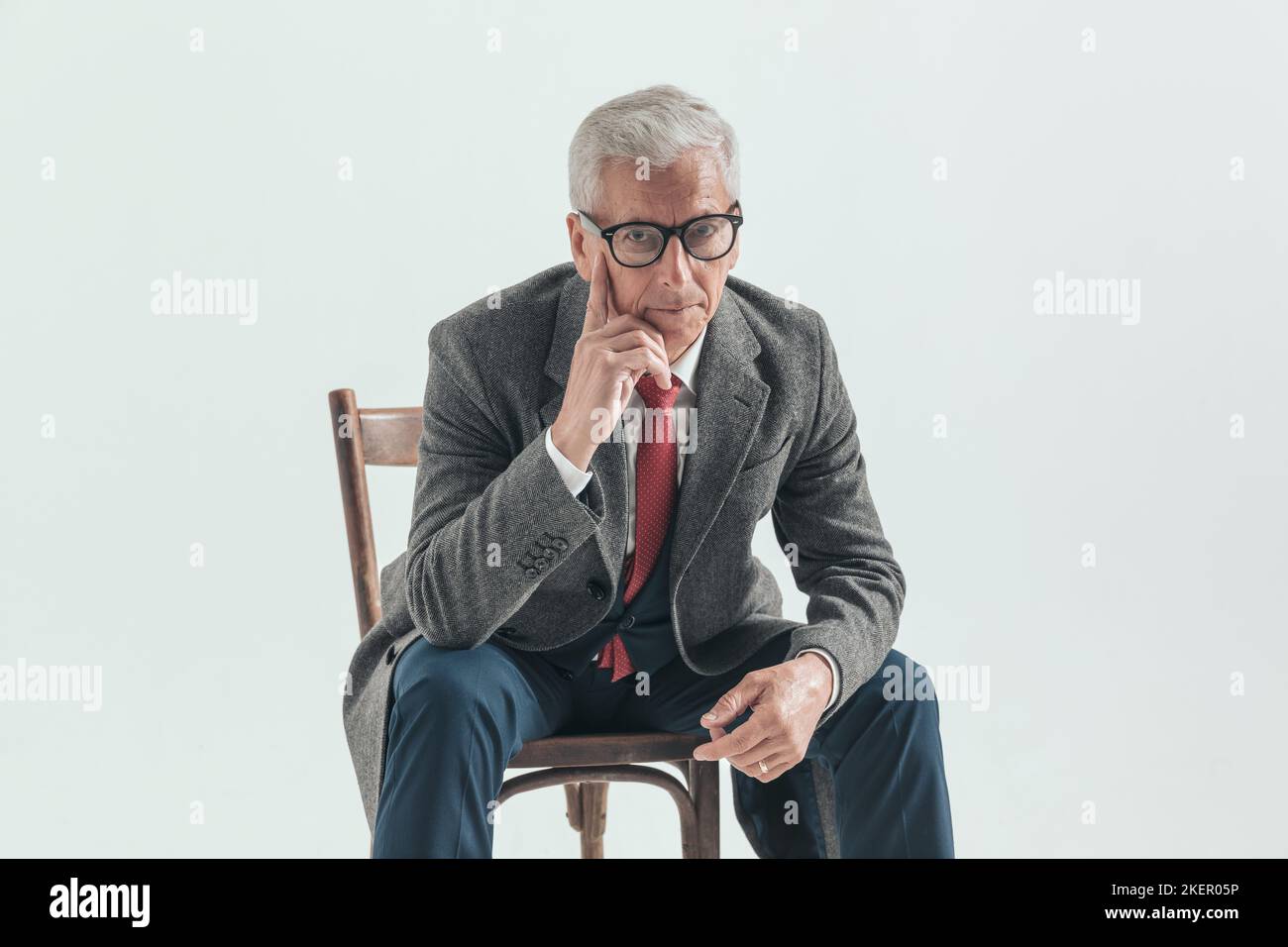 thoughtful man with grizzled hair touching face and thinking, posing ...