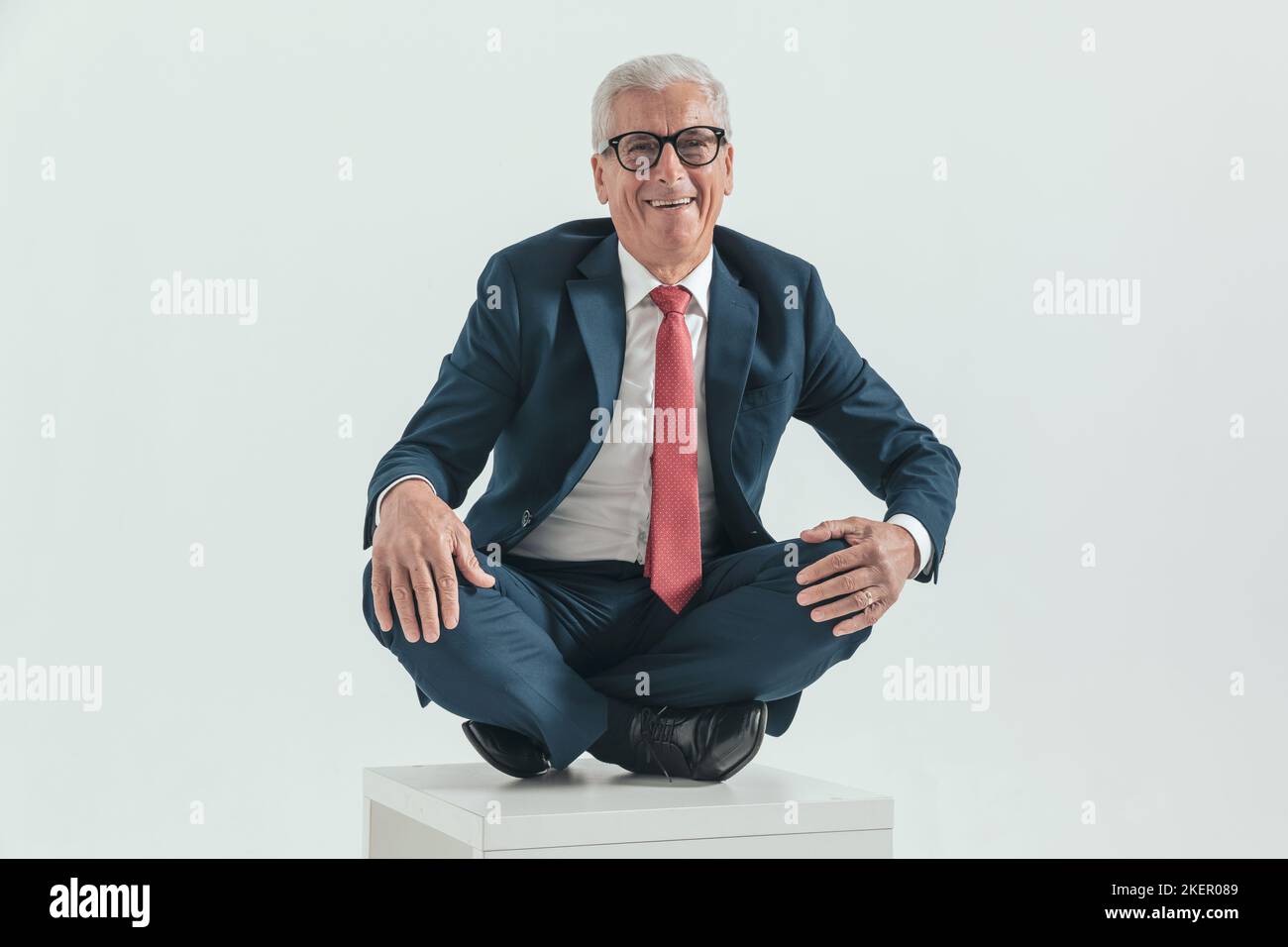 happy old man in his 60s sitting in a turkish pose and laughing while ...
