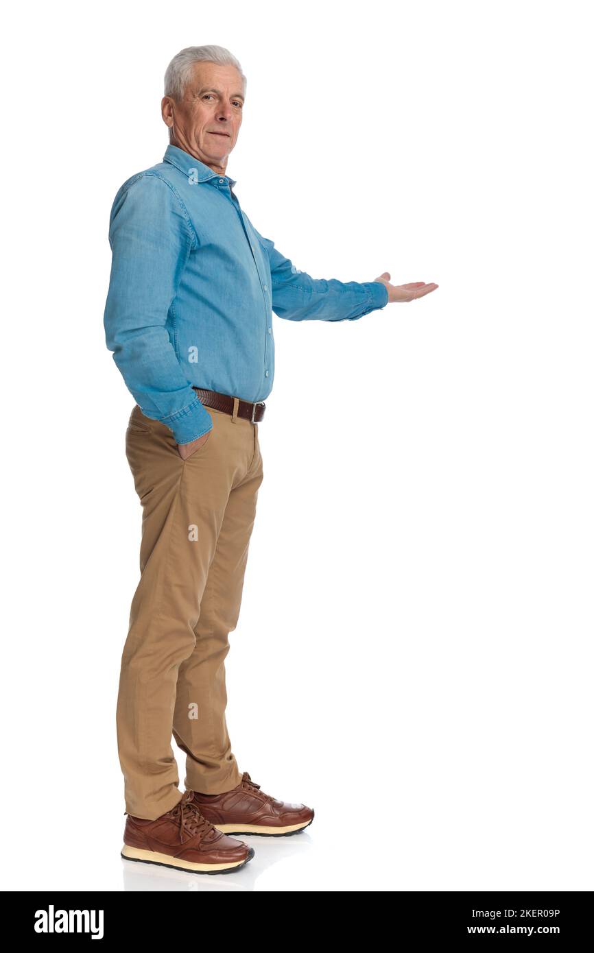 picture of serious old man posing with hand in pocket, showing to side ...