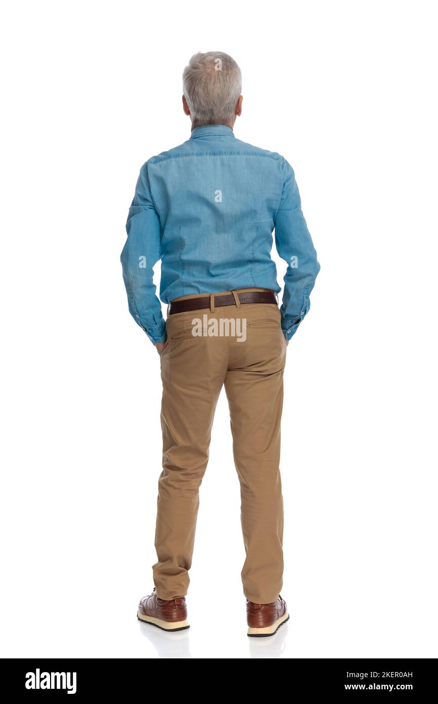 rear view of man with grizzled hair wearing denim shirt and chino pants ...