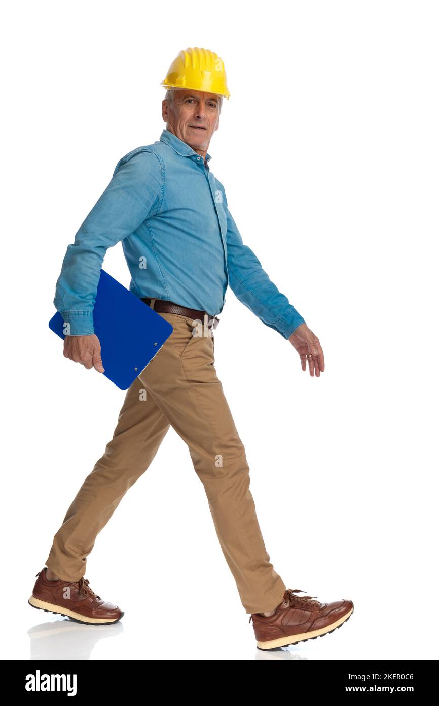 serious old man in his 60s walking to check the construction, wearing a ...