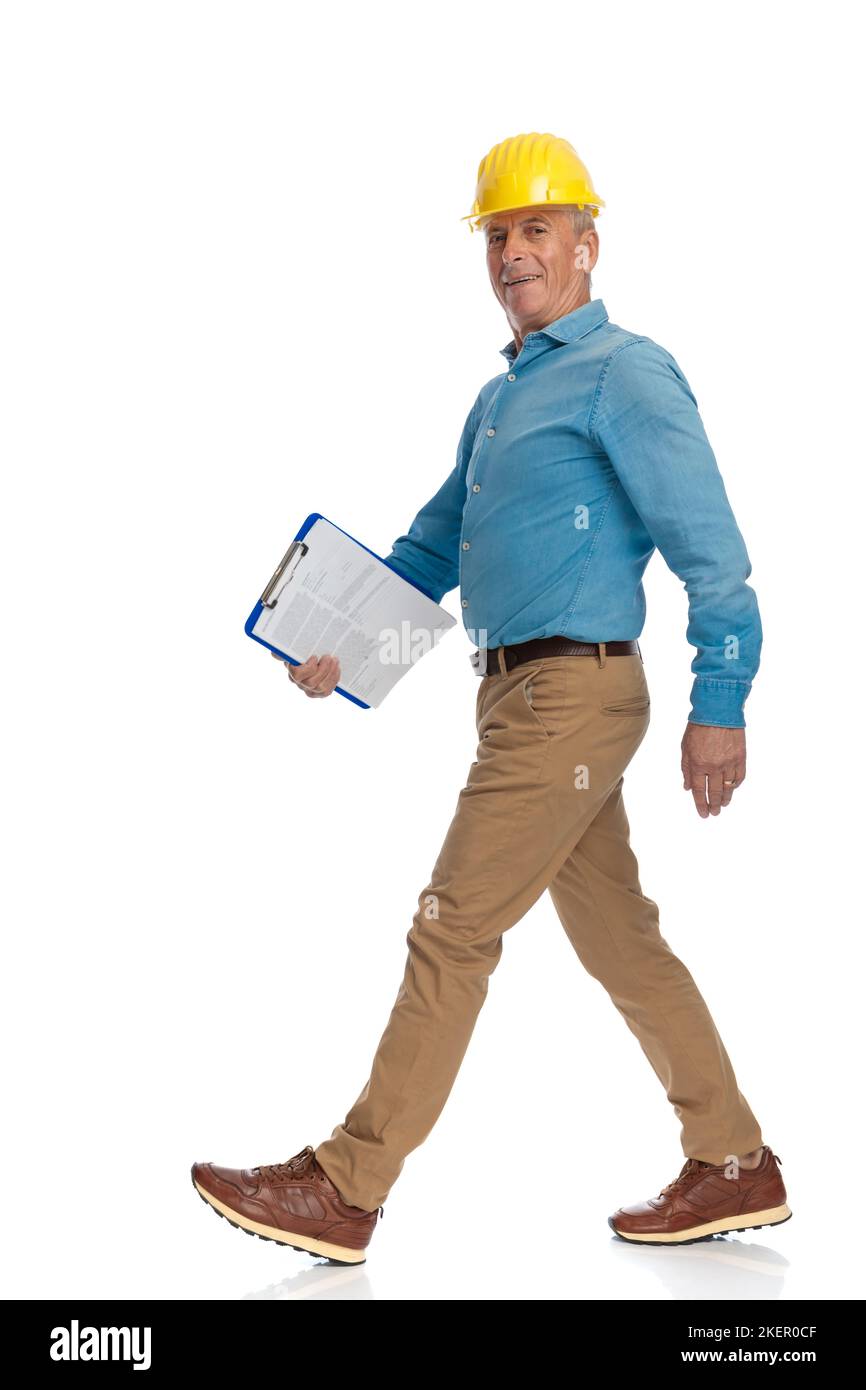 side view of old engineer with safety helmet and clipboard smiling and ...