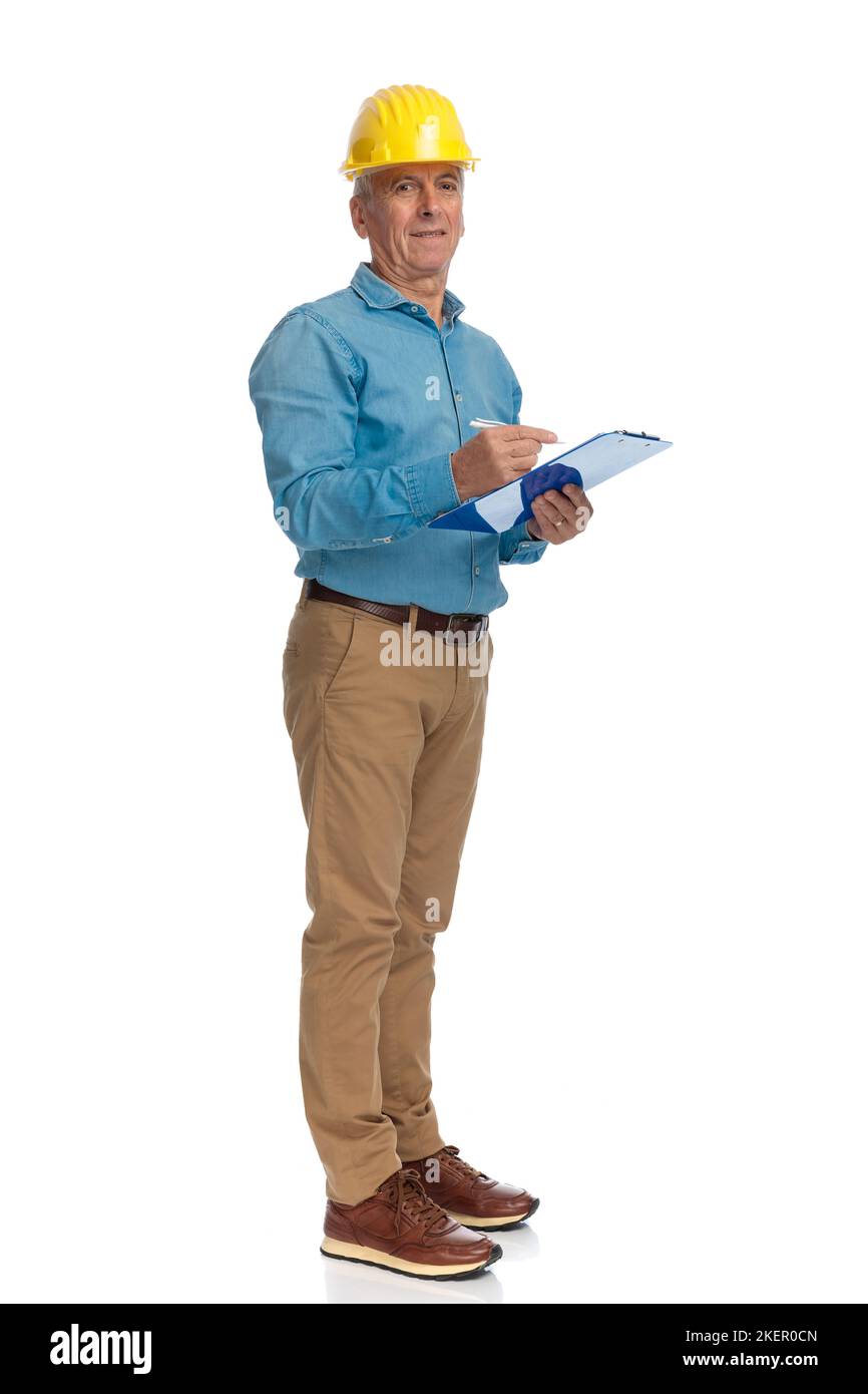 good looking old engineer with helmet holding clipboard and taking ...