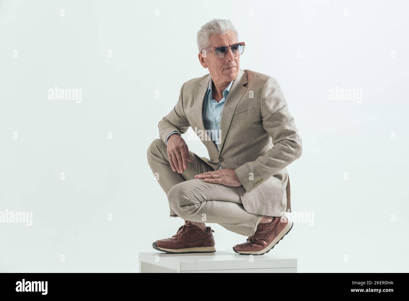 cool man in his 60s with grey hair looking to side and crouching in ...