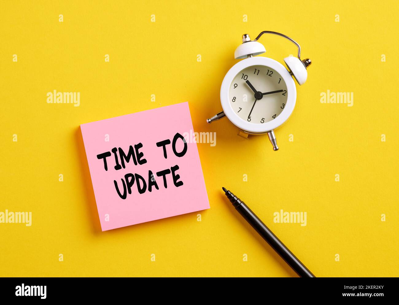 The word time to update on pink note paper with alarm clock and pen ...