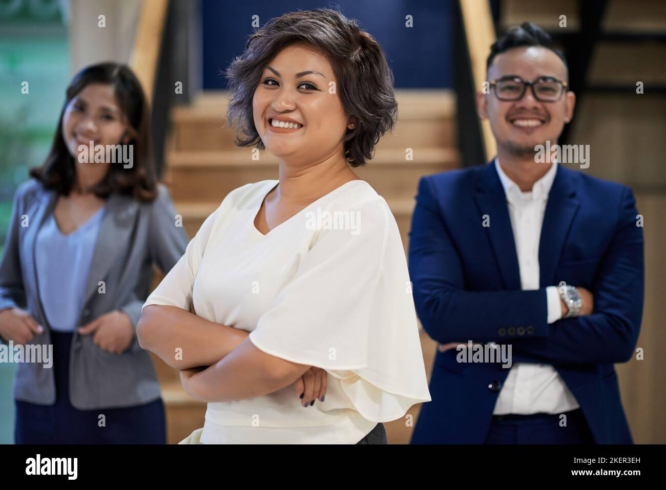 Cheerful pretty Asian business woman standing in from of her employees ...