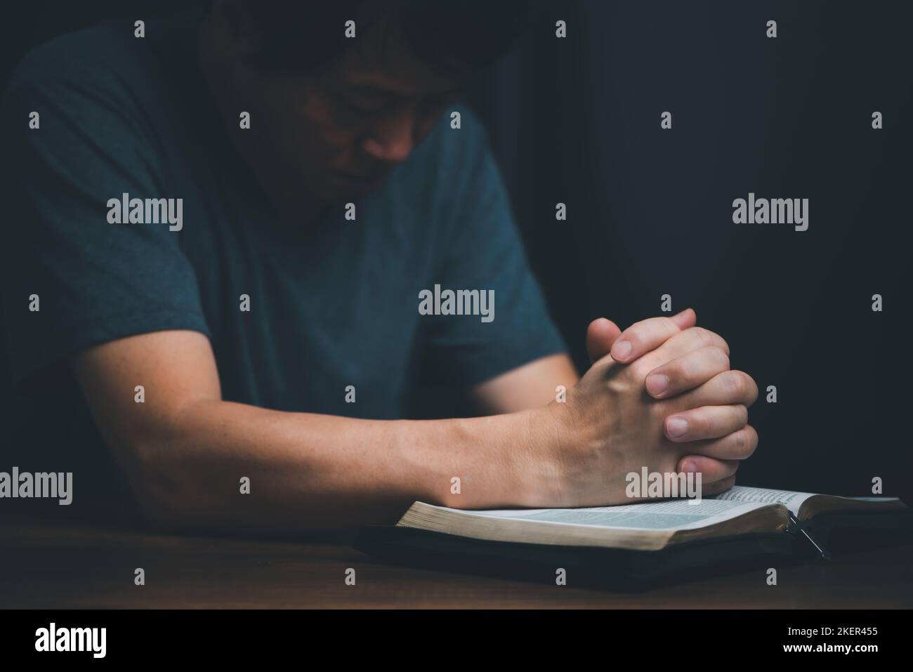 Man reading holy bible book and folding hands pray to God Stock Photo ...