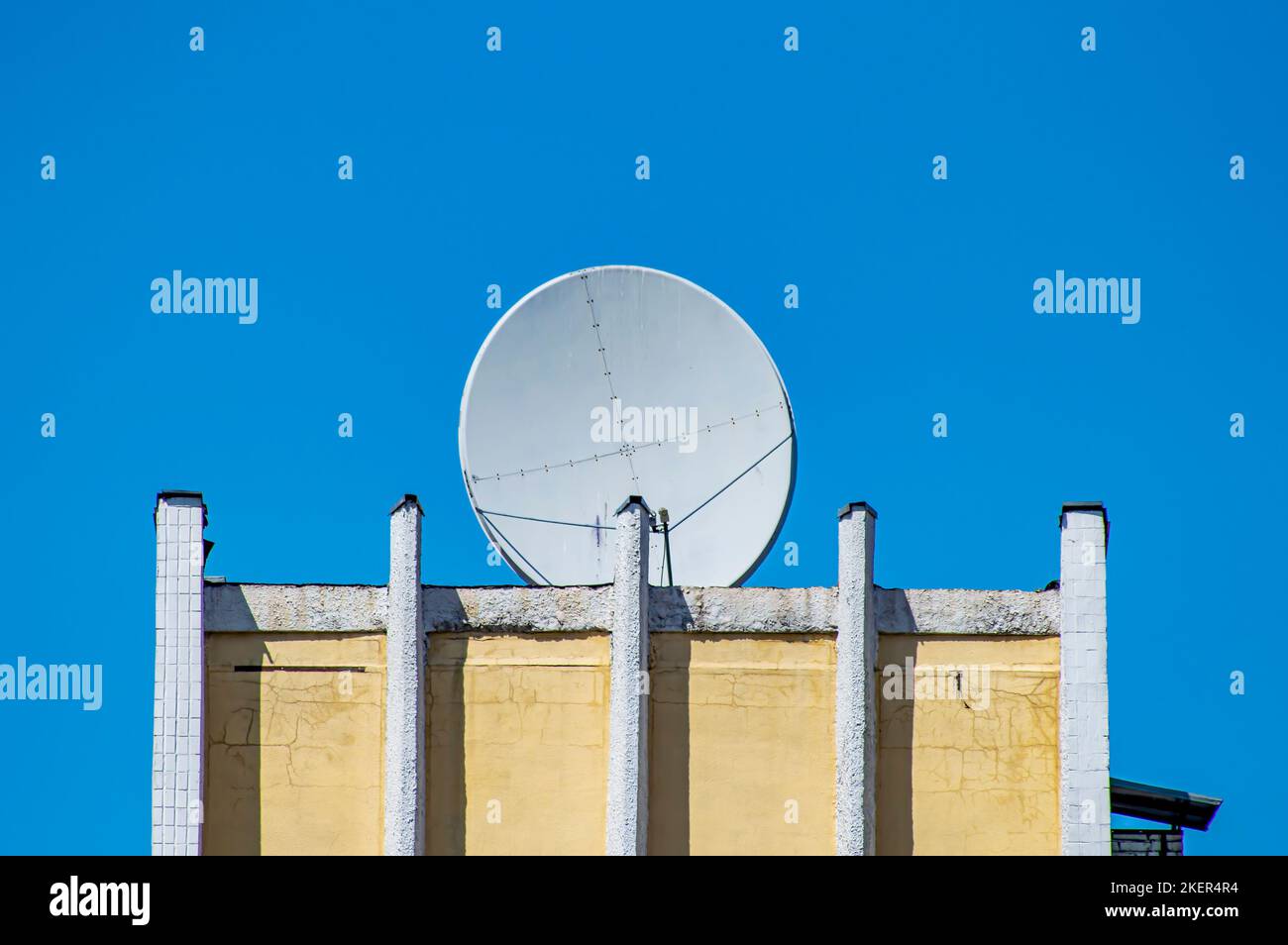 Satellite dish on the roof of a building against the blue sky. Antenna ...