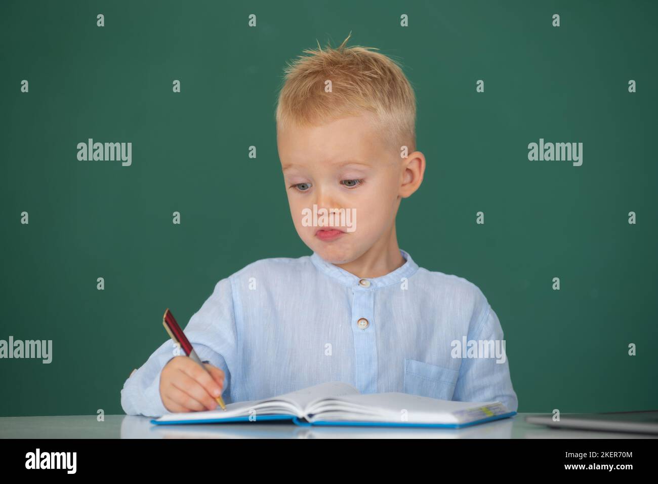 Kid writing in notebook in class. Back to school. School boy studying ...