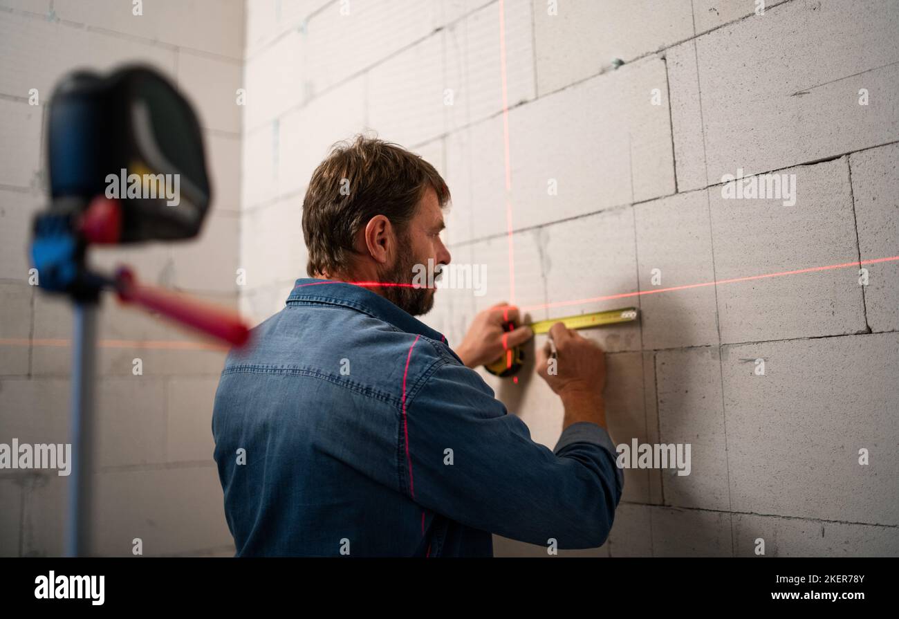 Handyman working on construction site, measuring wall Stock Photo - Alamy