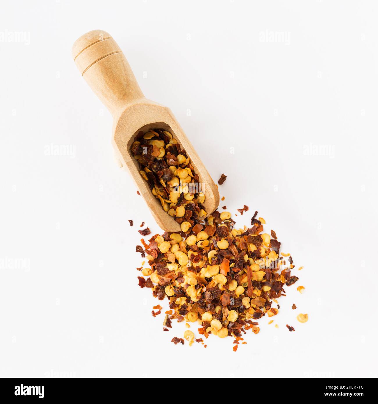 Wooden scoop full of crushed red cayenne pepper, dried chili flakes and ...