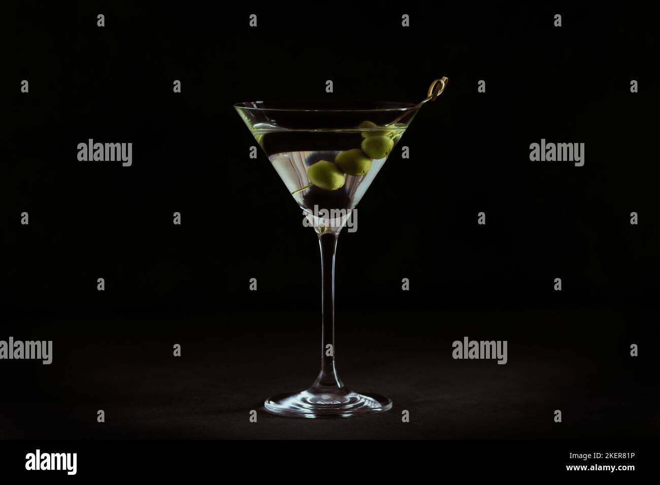 Glass of classic dry martini cocktail with olives on dark stone table ...