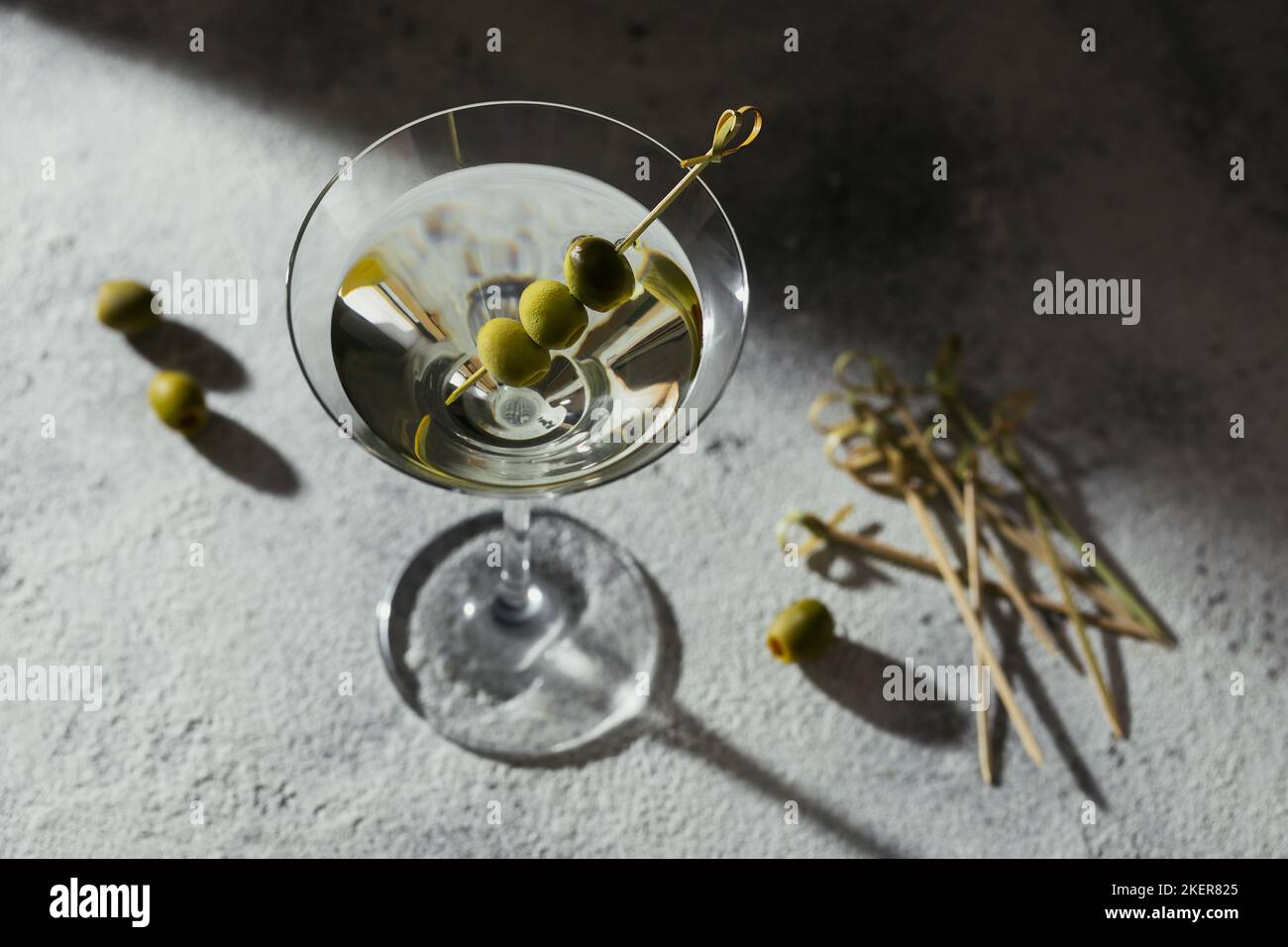 Glass of classic dry martini cocktail with olives on grey stone ...
