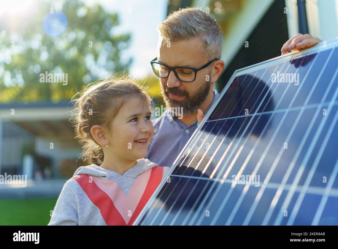 Father with his little daughter near their house with solar panels ...