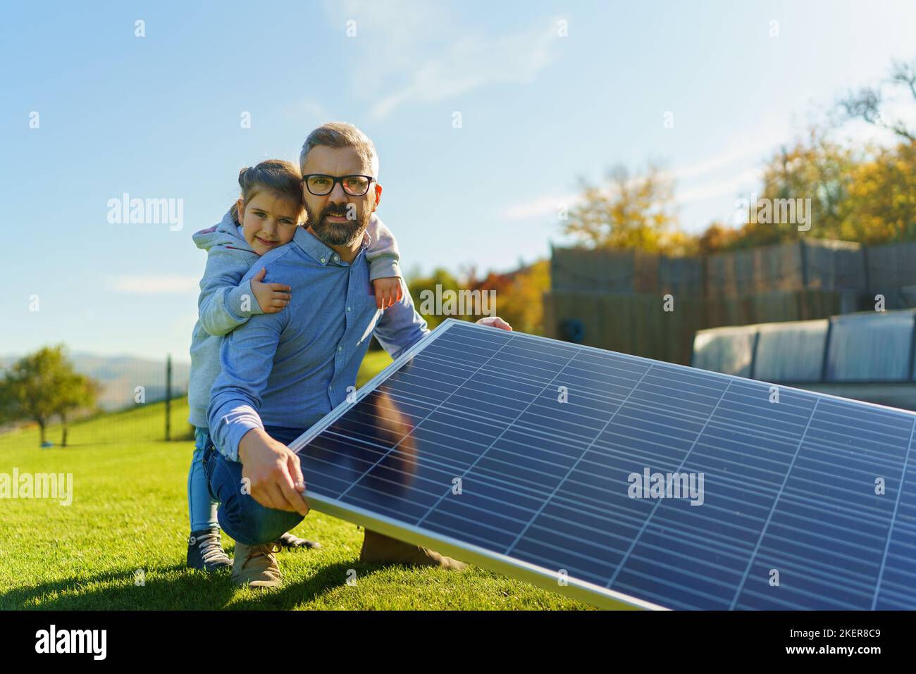 Father with his little daughter catching sun at solar panel,charging at ...