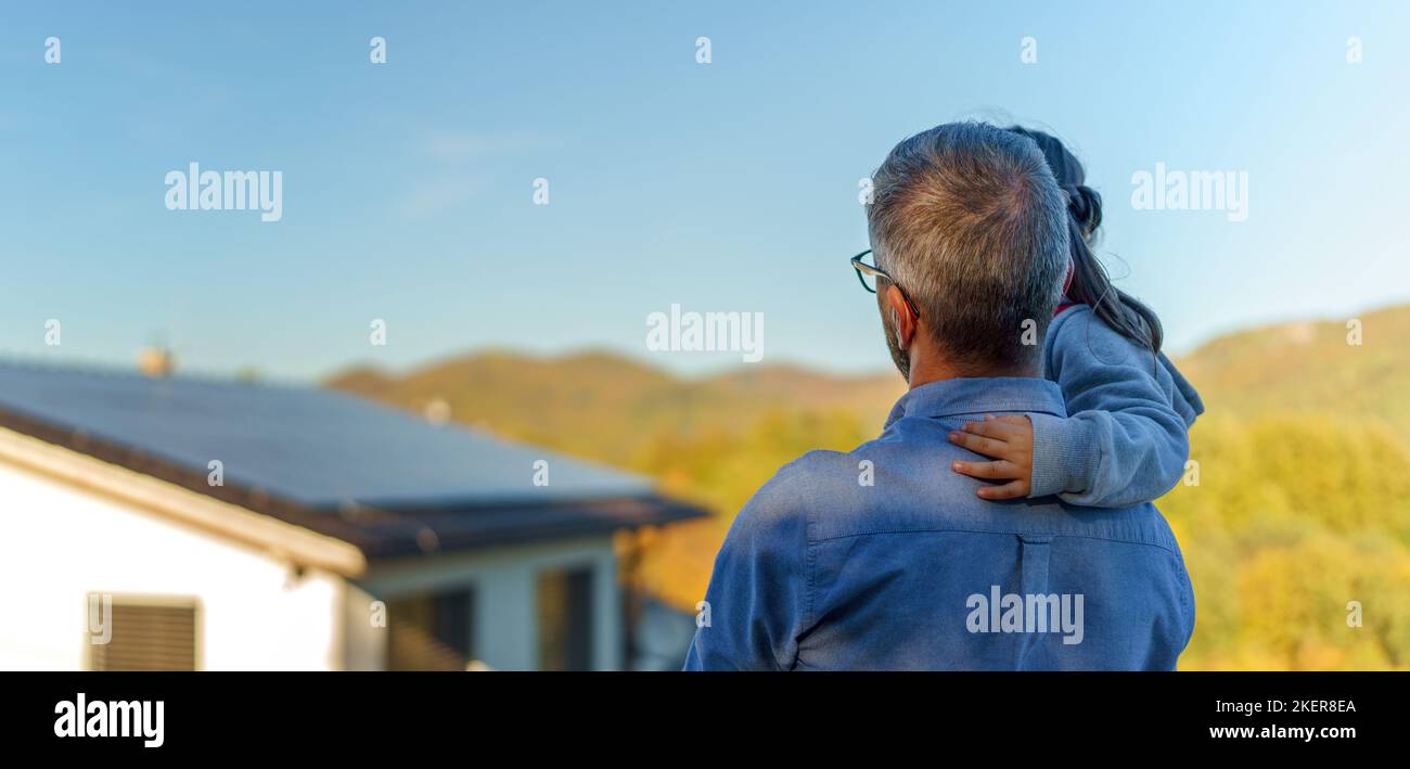 Rear view of dad holding her little girl in arms and looking at their ...