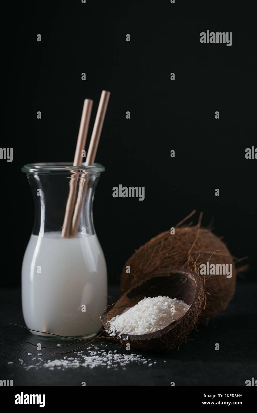 Bottle of coconut vegan milk with straws, whole coconut and flakes on ...