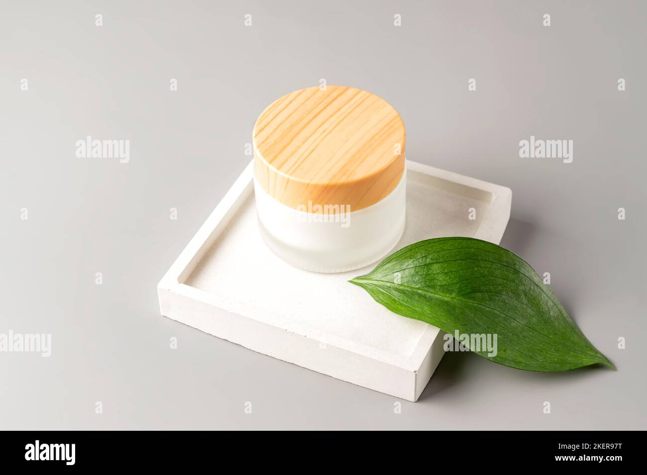 Moisturizing cream in frosted glass jar packaging on cocnrete tray on ...