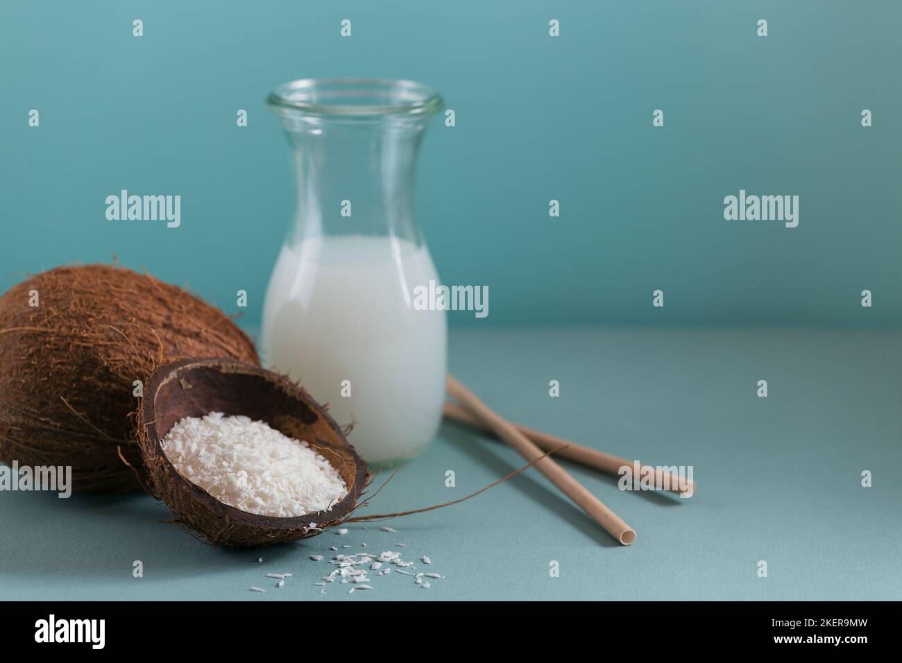 Bottle of coconut vegan milk with straws, whole coconut and flakes on a ...