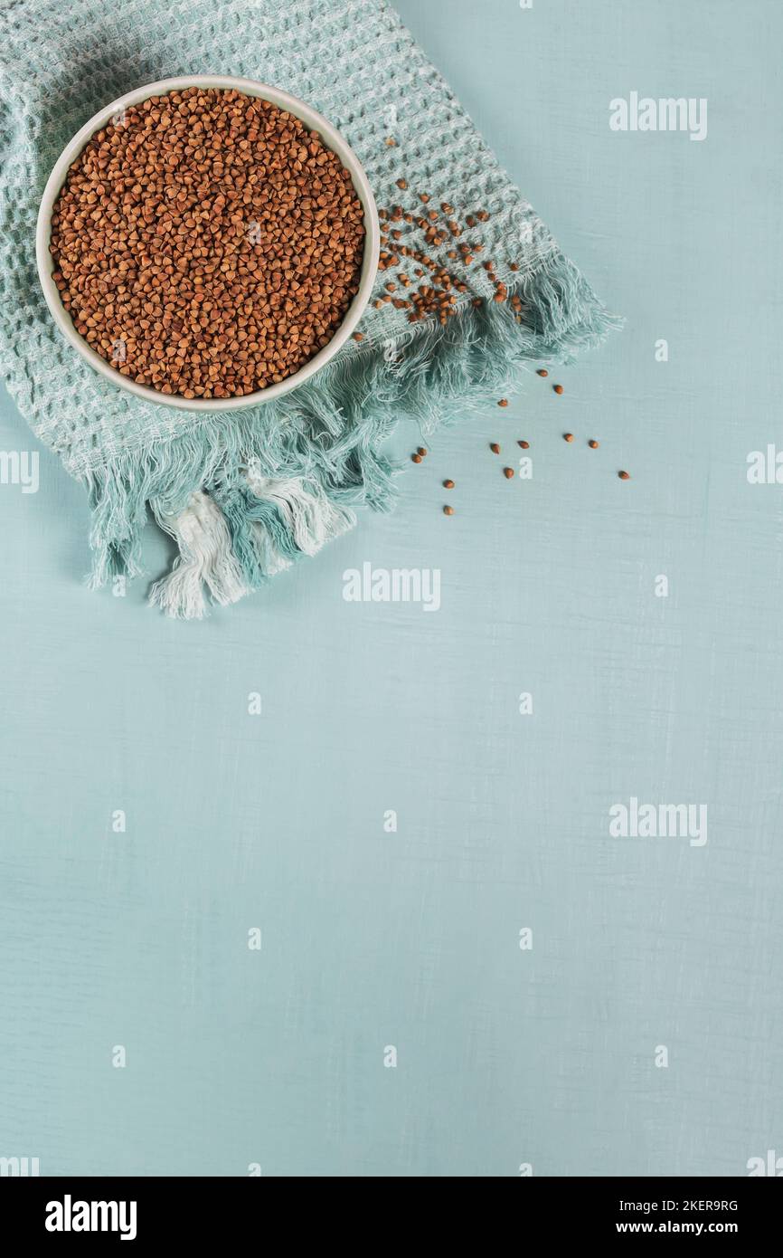 Bowl of dry raw buckwheat groats on a light blue background. Cooking ...