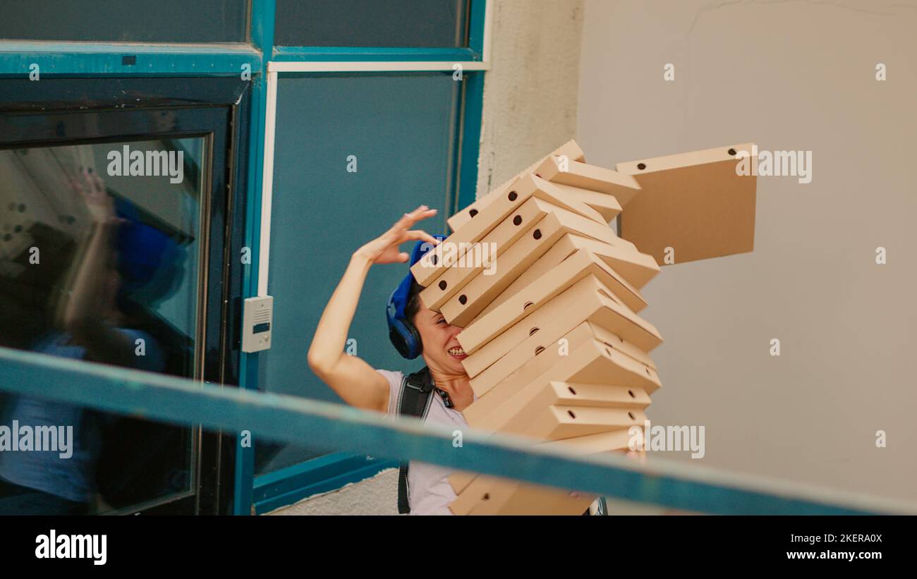 Female carrier trying to catch falling pizza boxes, acting scared and ...