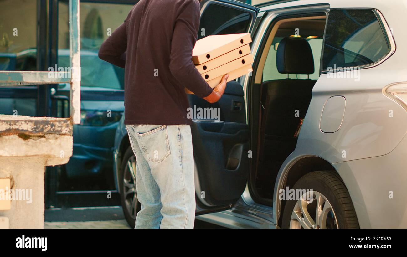 African american male courier leaving car to deliver pizza boxes at ...