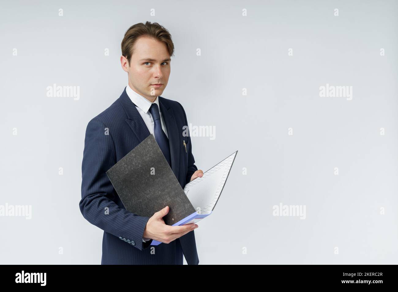 A businessman in a blue suit holds folders on a white background ...