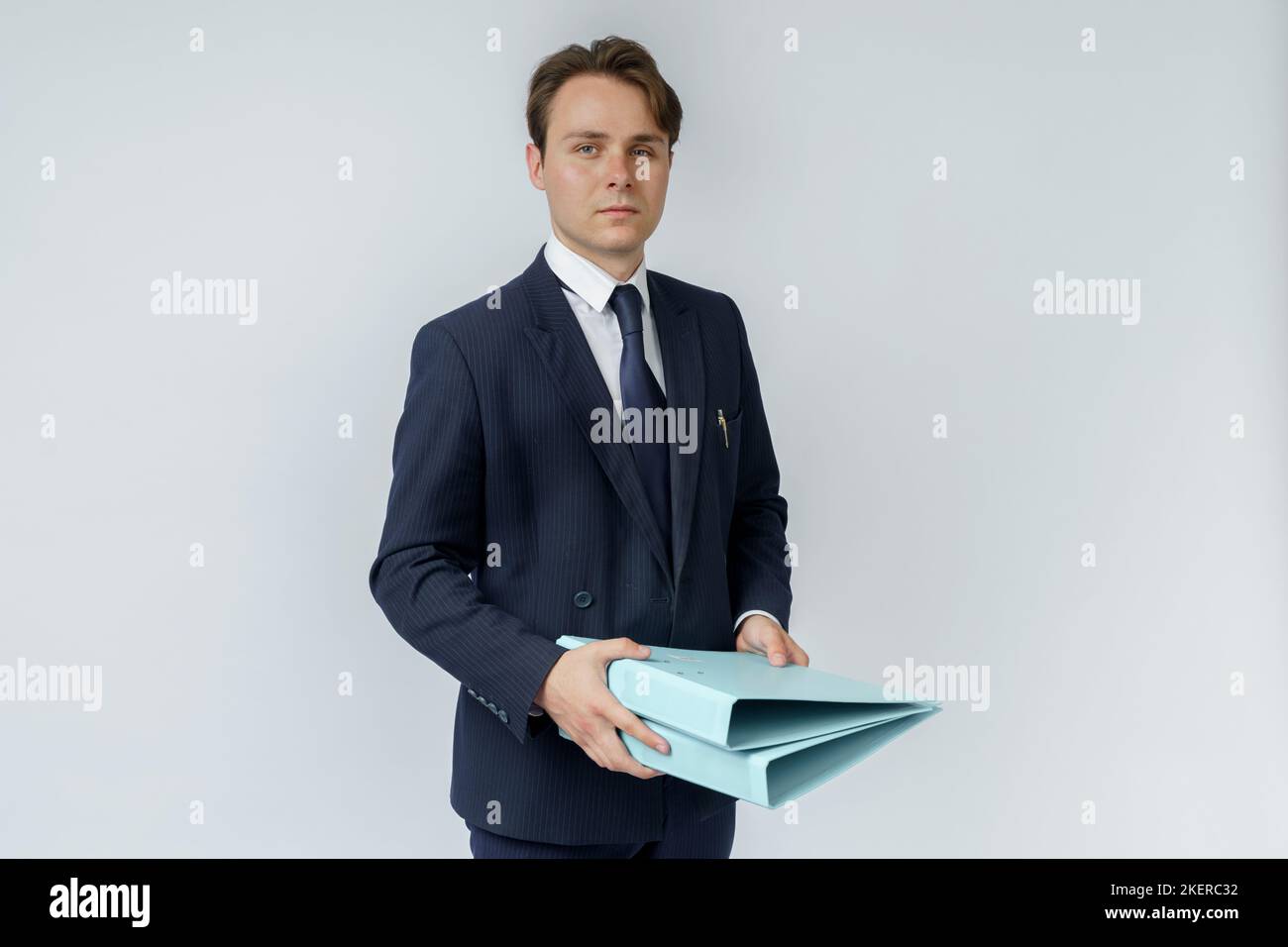 A businessman in a blue suit holds folders on a white background ...