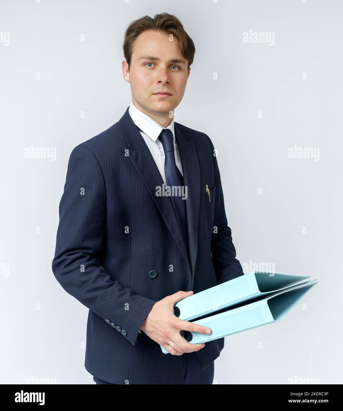 A businessman in a blue suit holds folders on a white background ...