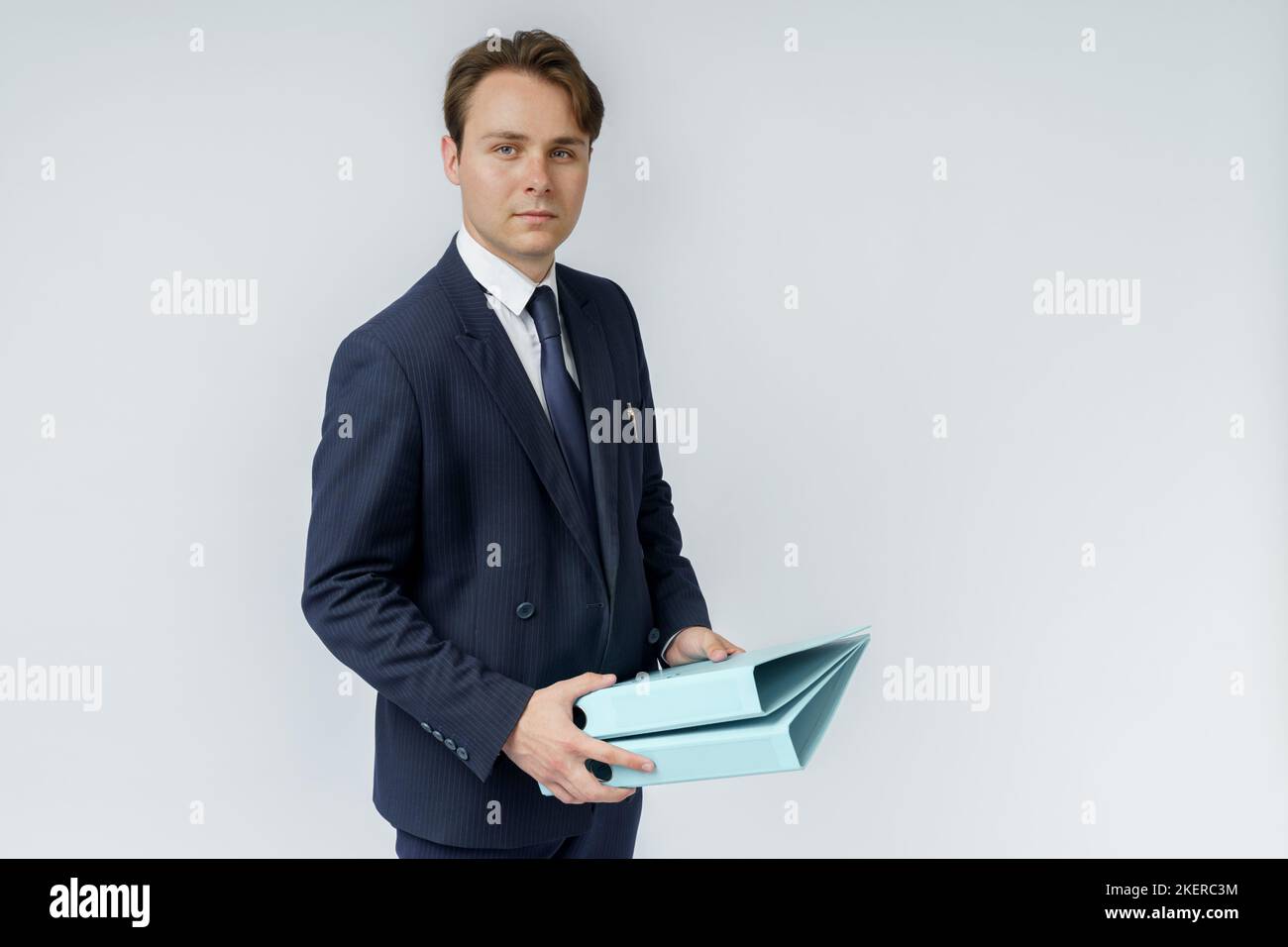 A businessman in a blue suit holds folders on a white background ...