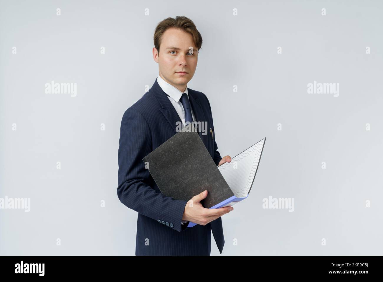 A businessman in a blue suit holds folders on a white background ...