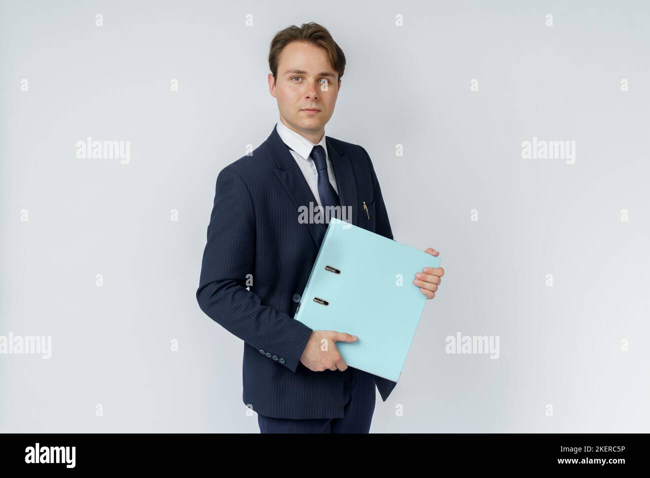 A businessman in a blue suit holds folders on a white background ...