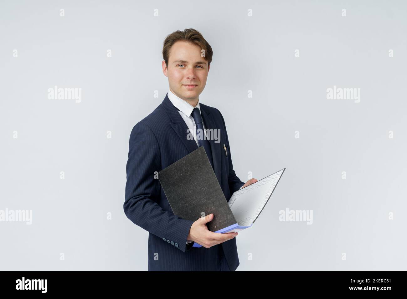 A businessman in a blue suit holds folders on a white background ...