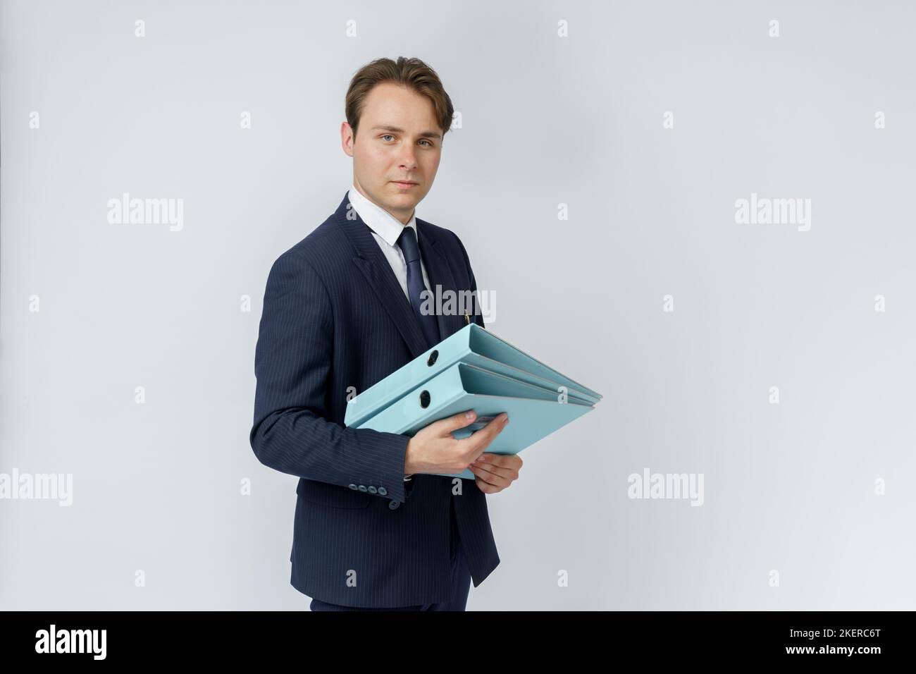 A businessman in a blue suit holds folders on a white background ...