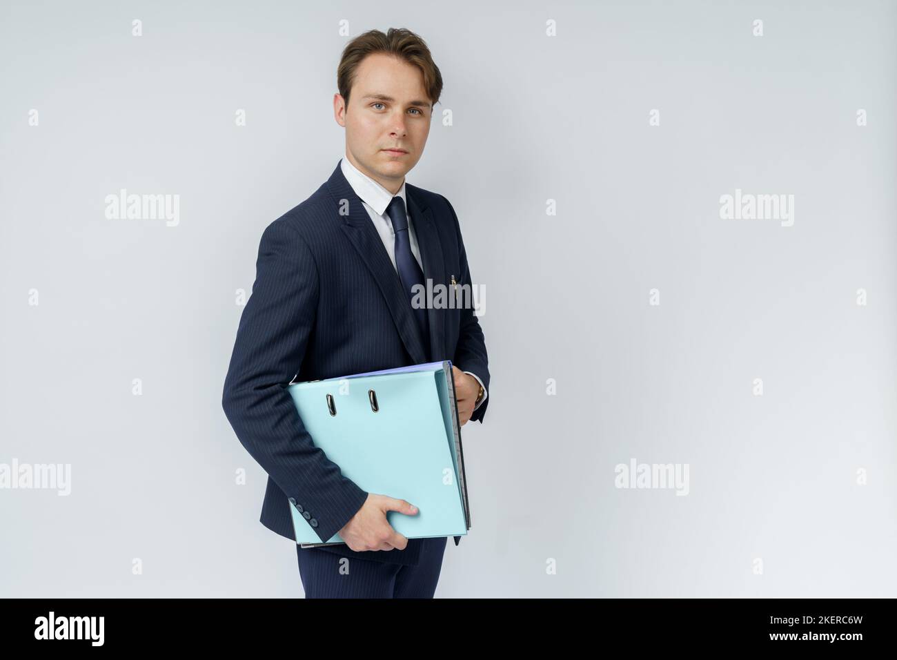 A businessman in a blue suit holds folders on a white background ...
