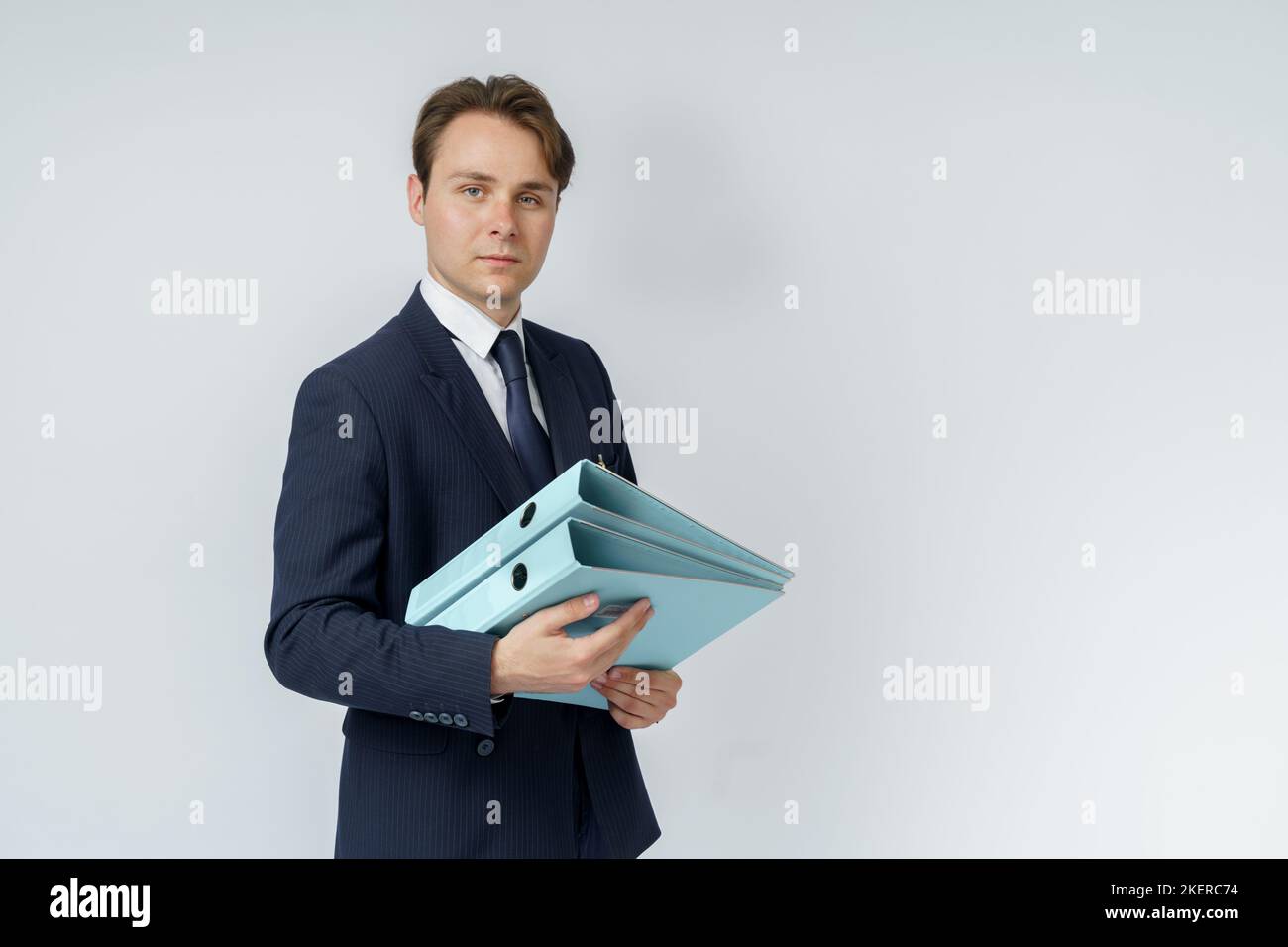 A businessman in a blue suit holds folders on a white background ...