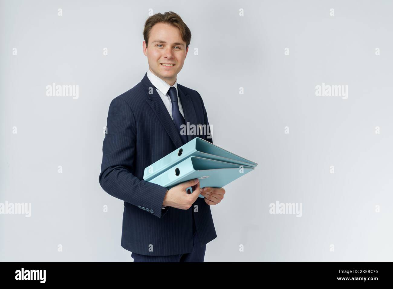 A businessman in a blue suit holds folders on a white background ...