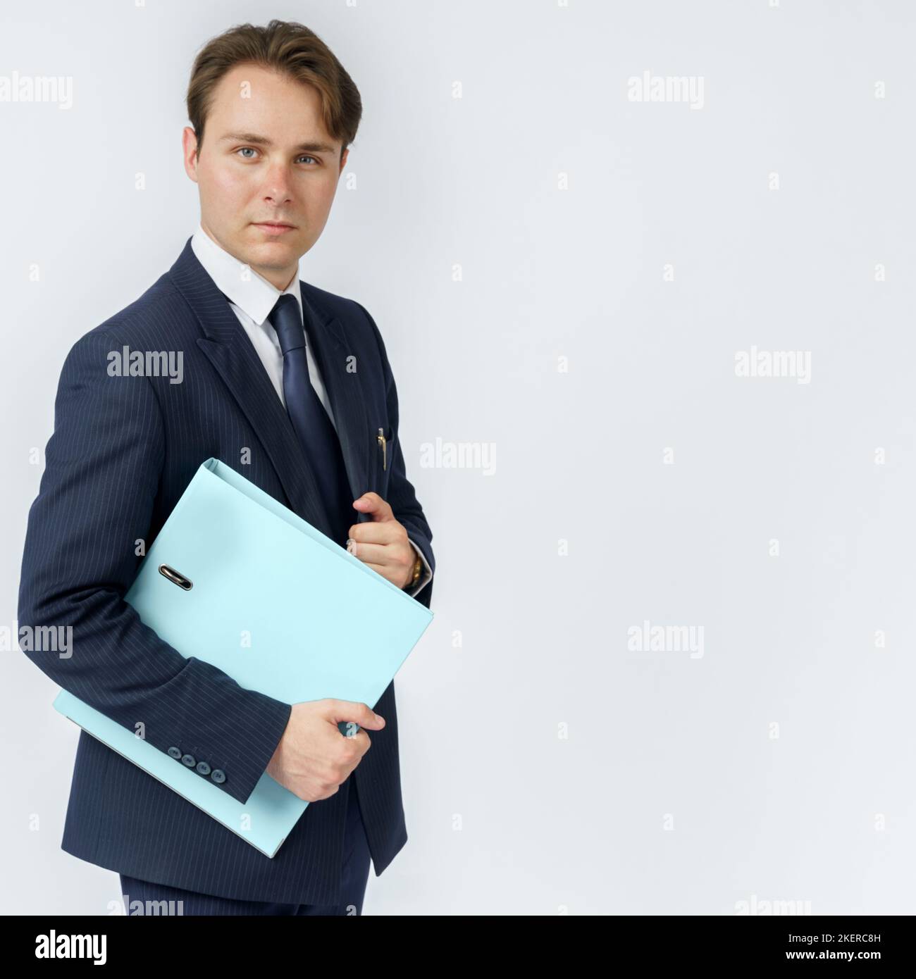 A businessman in a blue suit holds folders on a white background ...