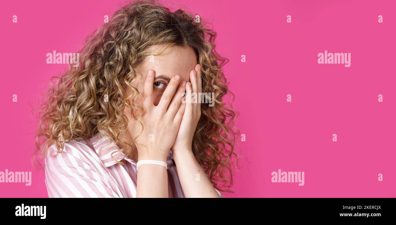 Portrait of shy, timid or ashamed pretty girl covering face and peeping ...