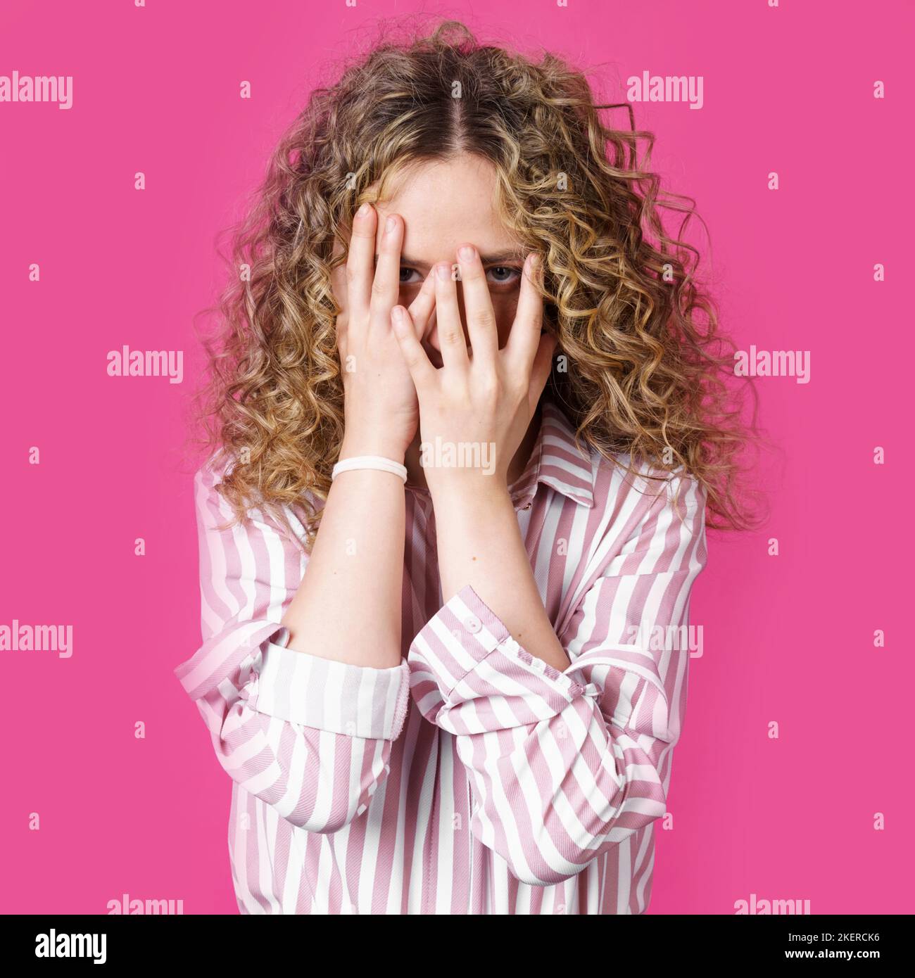 Portrait of shy, timid or ashamed pretty girl covering face and peeping ...