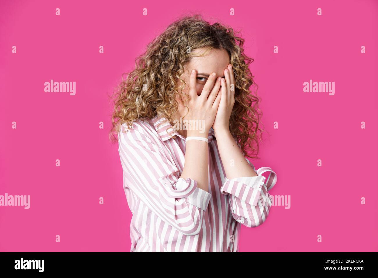 Portrait of shy, timid or ashamed pretty girl covering face and peeping ...
