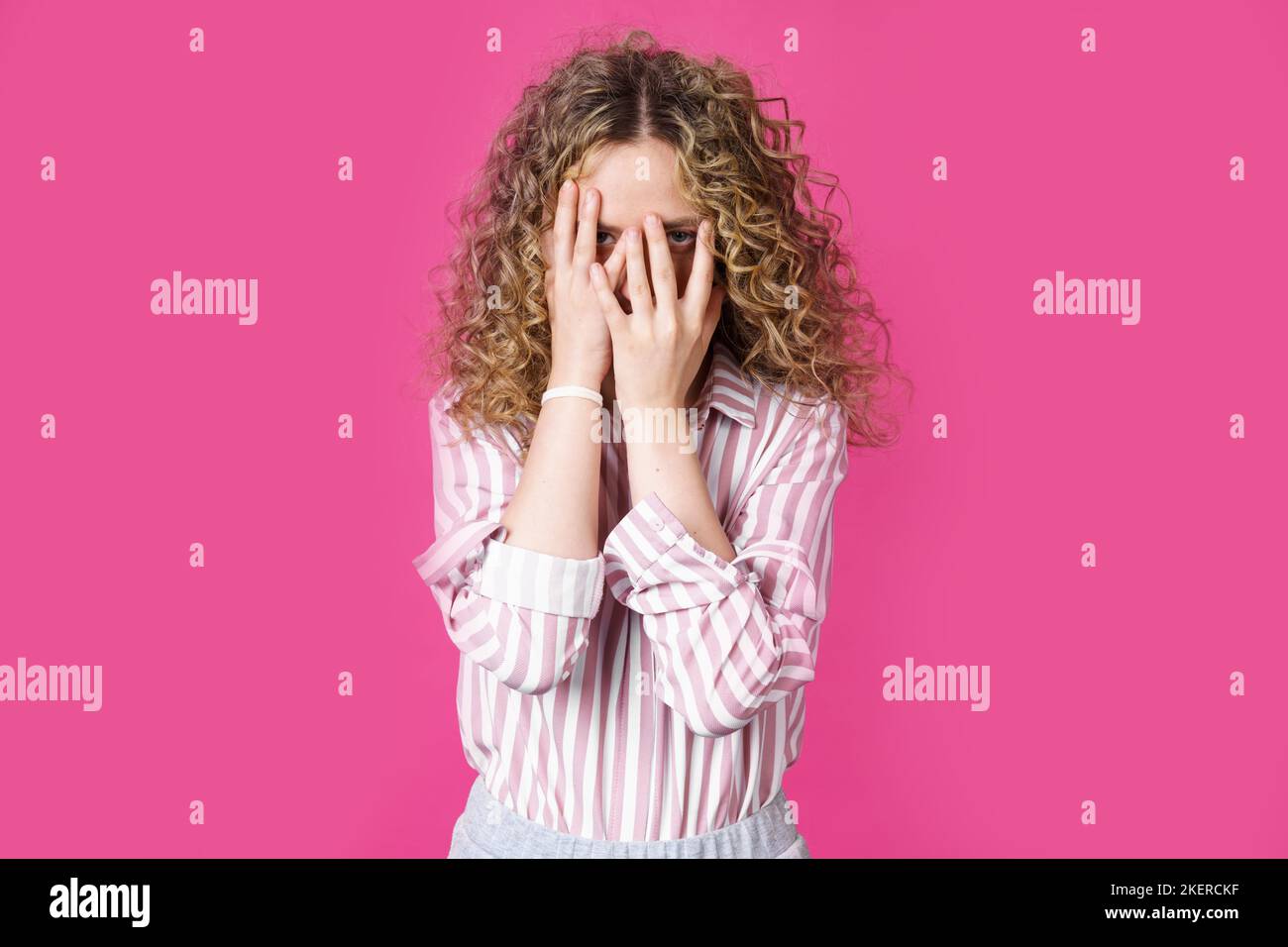 Portrait of shy, timid or ashamed pretty girl covering face and peeping ...