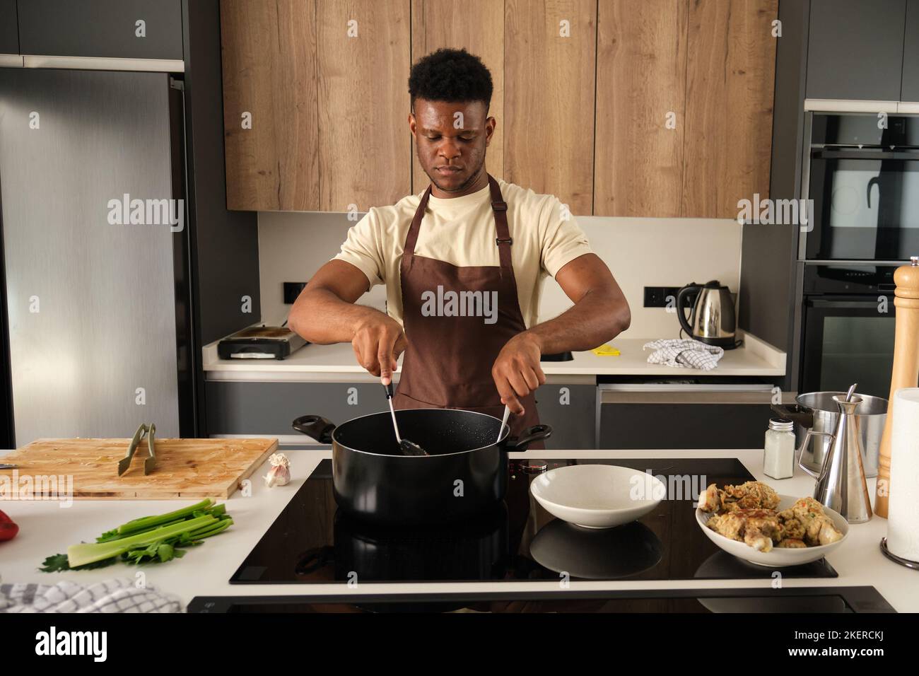 Young black man preparing fried chicken mince with vegetables recipe ...