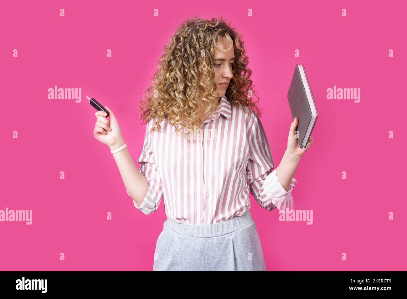 Fashionable woman in a striped shirt holding a diary and a marker ...
