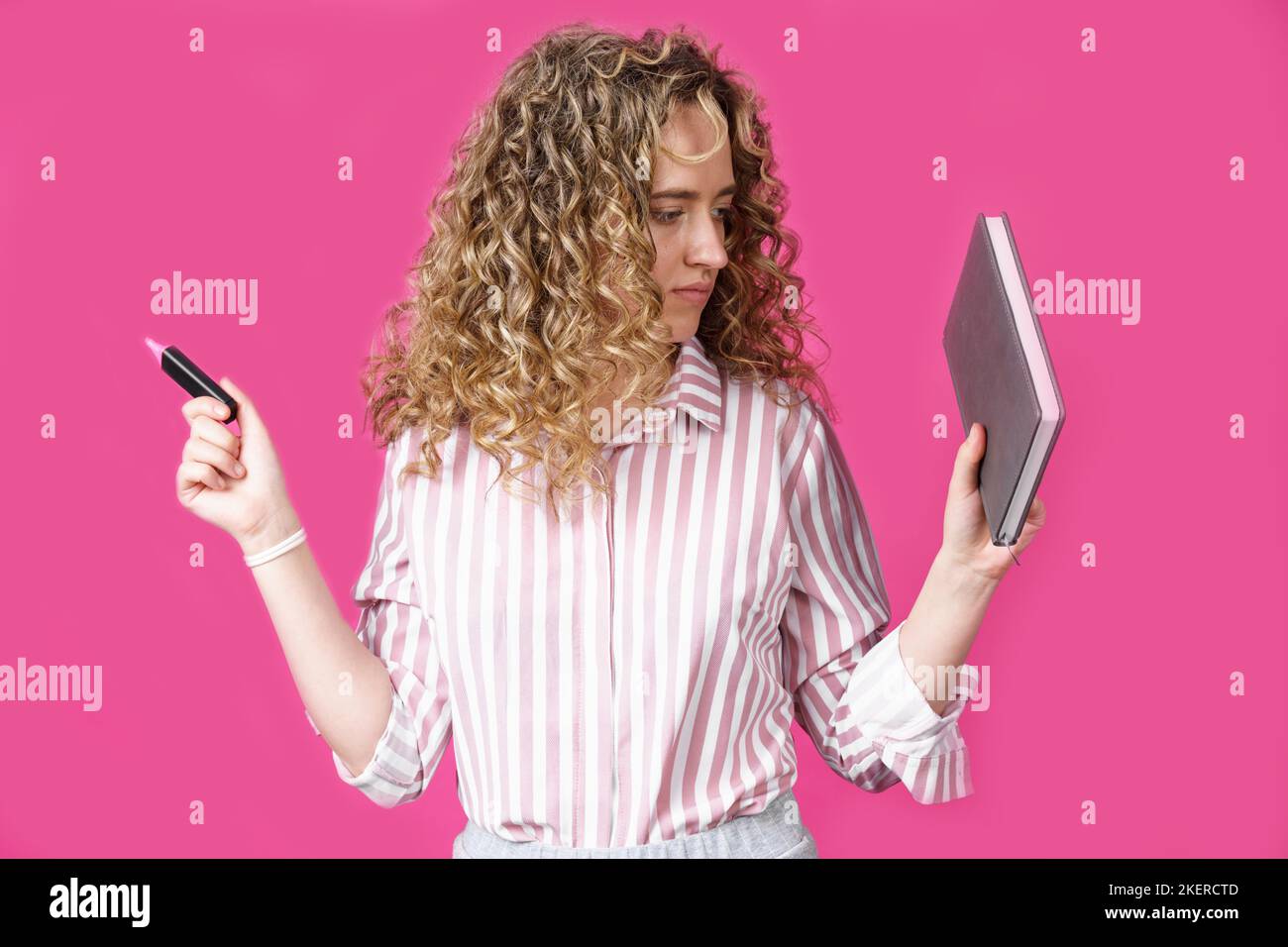 Fashionable woman in a striped shirt holding a diary and a marker ...