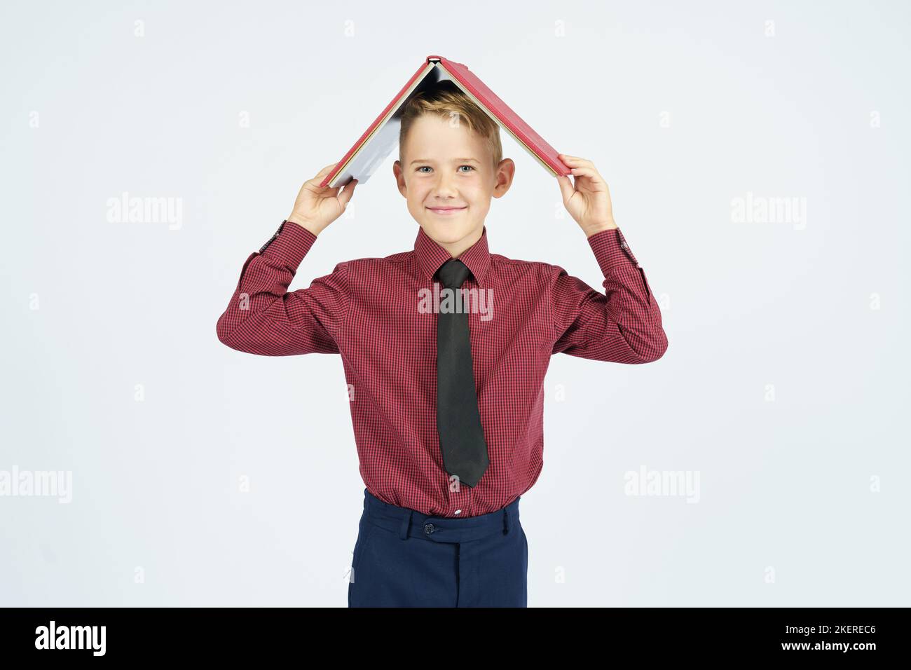 Pupil put an open book on his head and smiles, isolated background ...