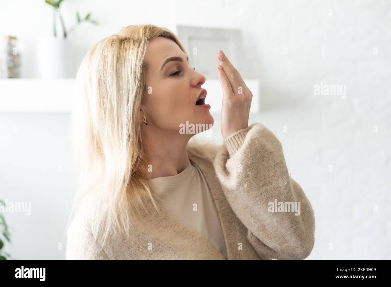 Health Care: Woman checking her breath with hand. Closeup portrait ...