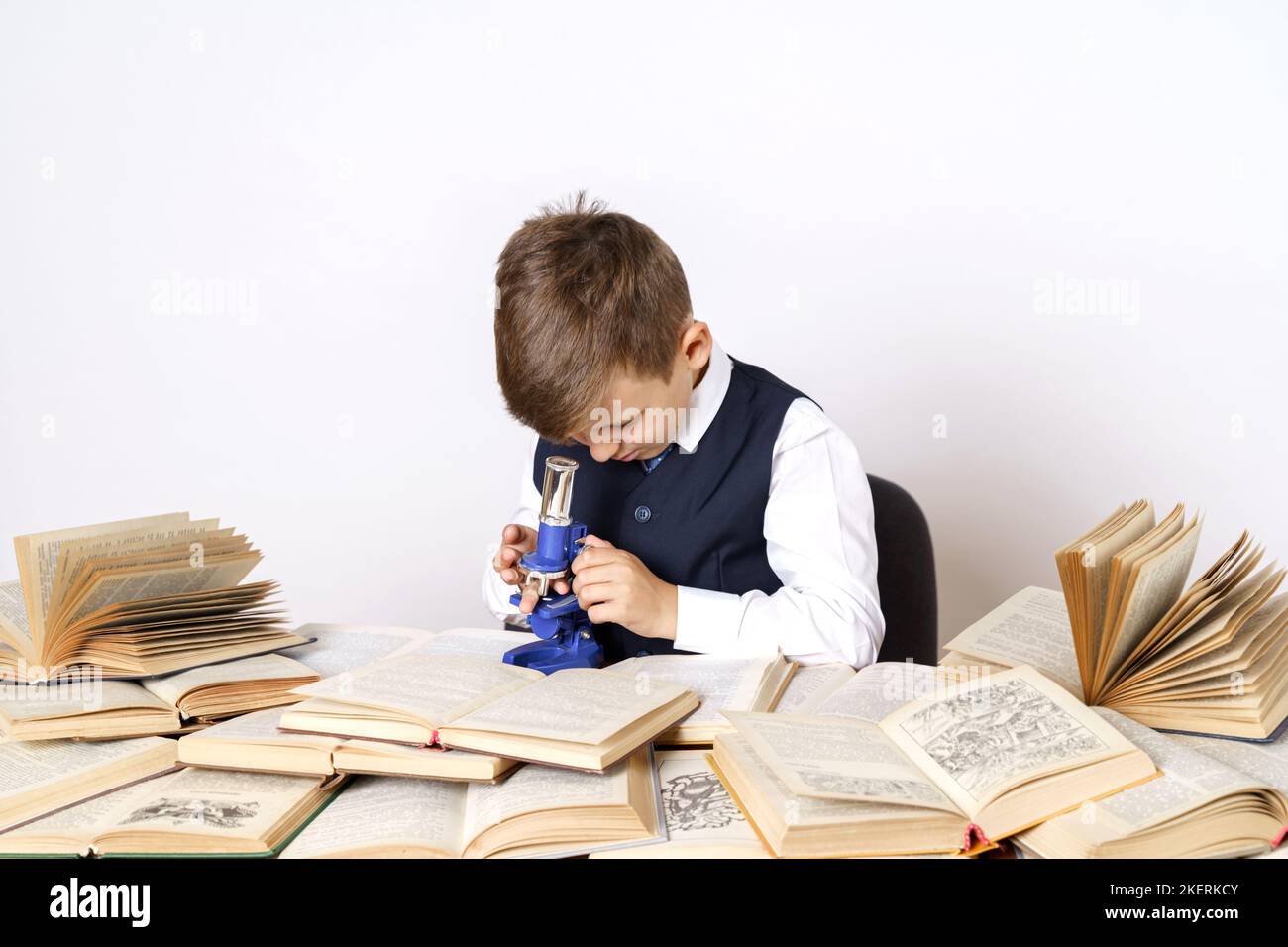 Education concept. A student does homework, looks through a microscope ...