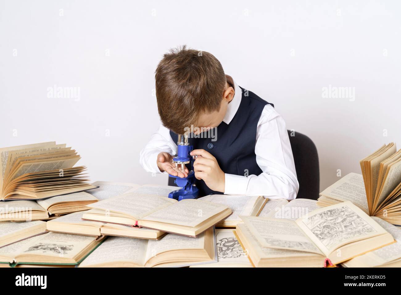 Education concept. A student does homework, looks through a microscope ...